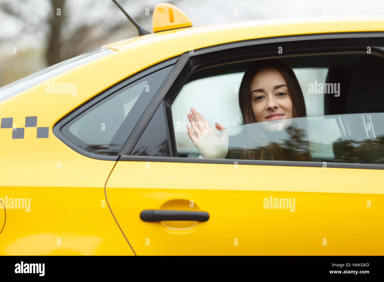 Pretty woman waves hand from window of yellow cab Stock Photo - Alamy
