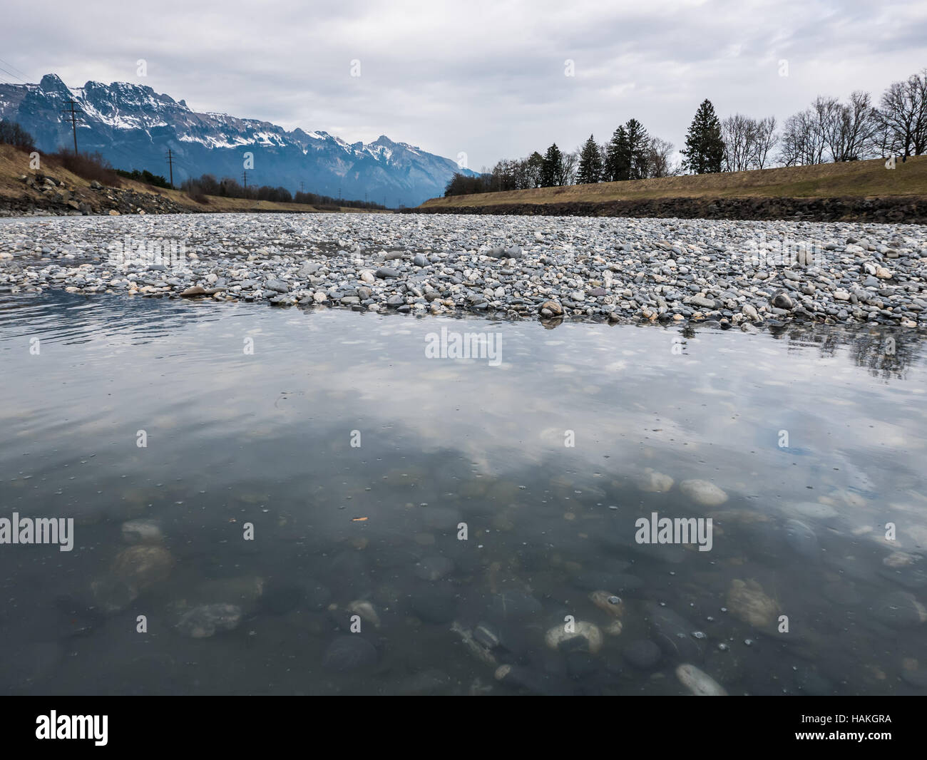 Rocks next to the river Rhein with the mountains (the Swiss alps) in ...