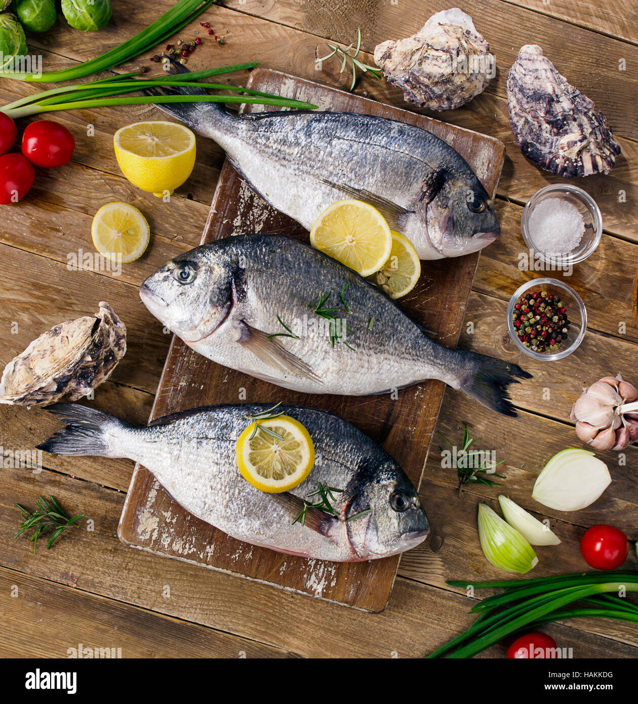 Fresh fish with herbs, spices and vegetables on wooden background ...