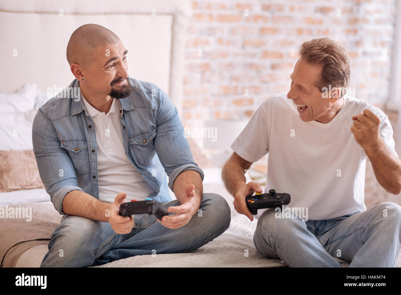 Delighted two men playing with game console at home Stock Photo - Alamy