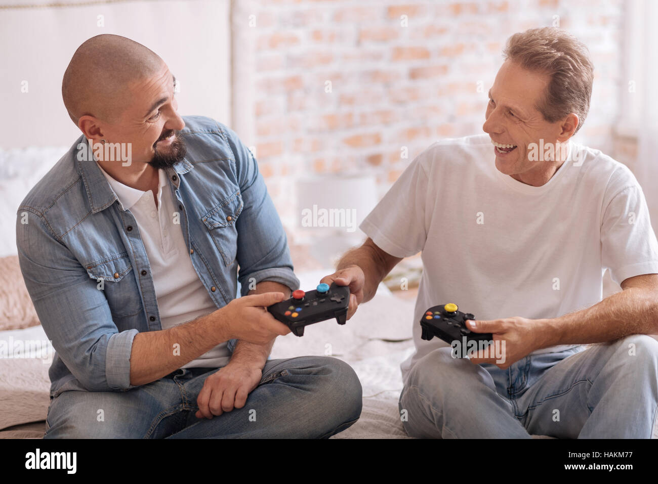 Delighted friends holding game consoles in the bedroom Stock Photo - Alamy