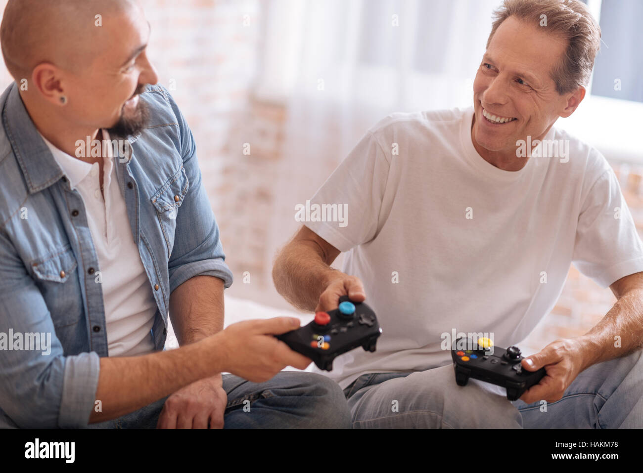 Smiling male friends holding game consoles at home Stock Photo - Alamy