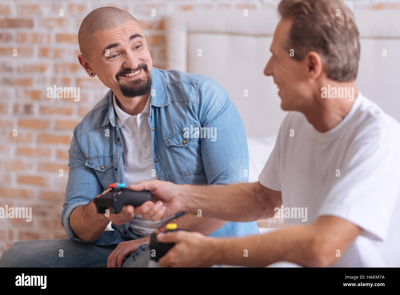 Delighted friends exchanging game consoles at home Stock Photo - Alamy