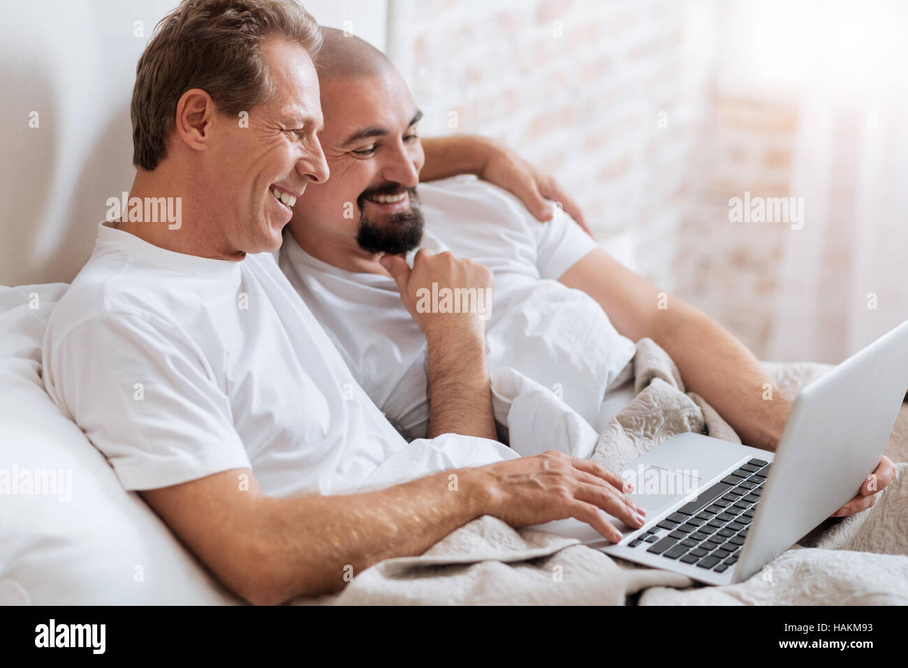 Happy gay couple using the laptop and hugging Stock Photo - Alamy