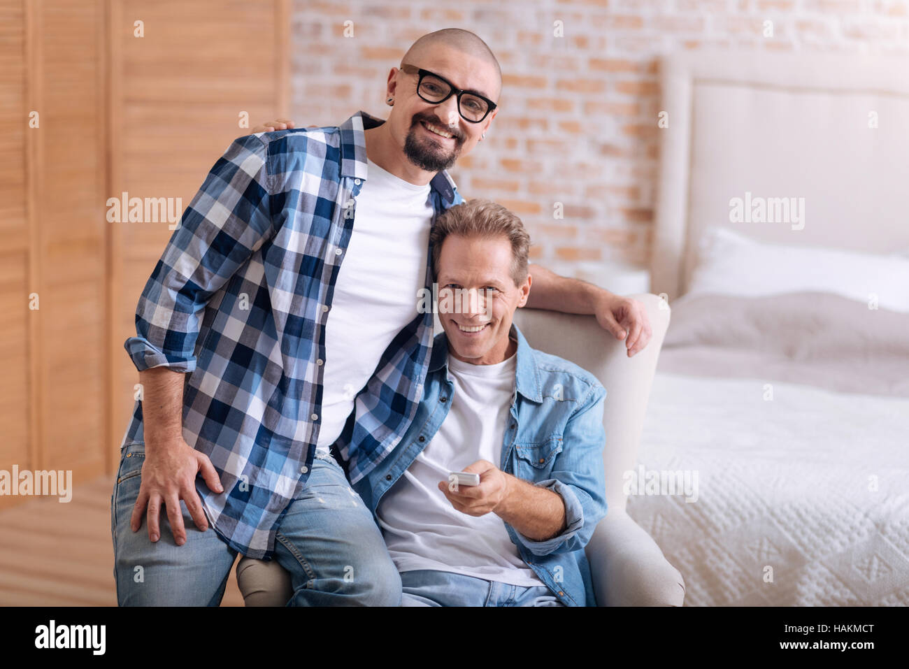 Positive homosexual couple watching television together Stock Photo - Alamy