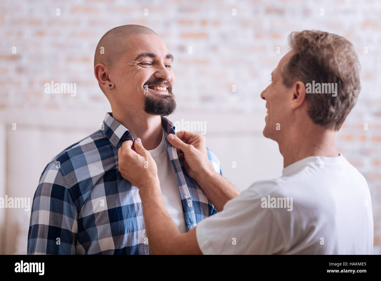 Positive aged man helping his partner to get ready Stock Photo - Alamy