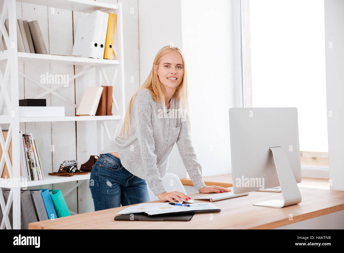 Happy attractive business woman standing and working with computer in ...