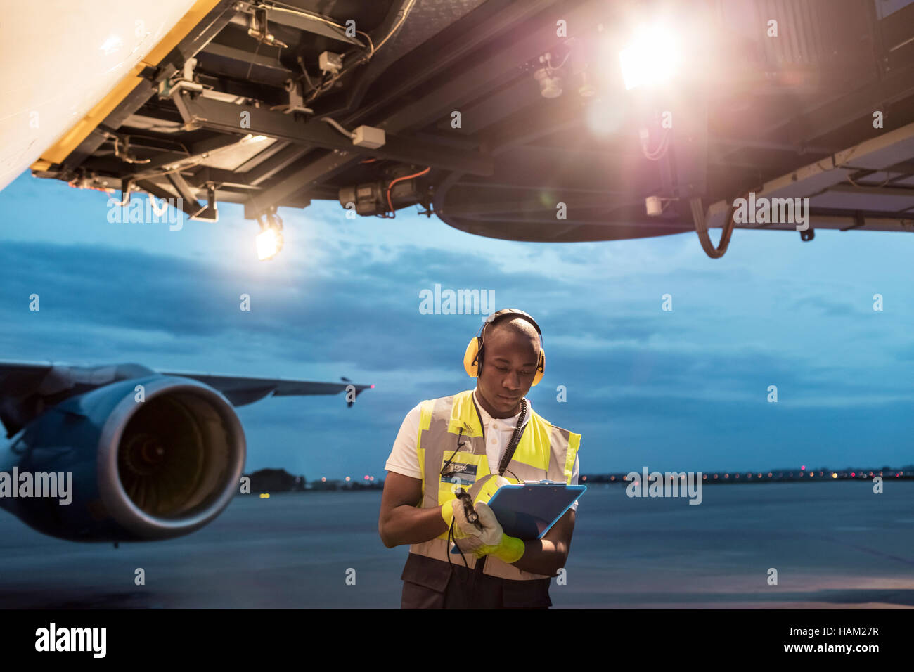 Airport ground crew worker with clipboard under airplane on tarmac ...