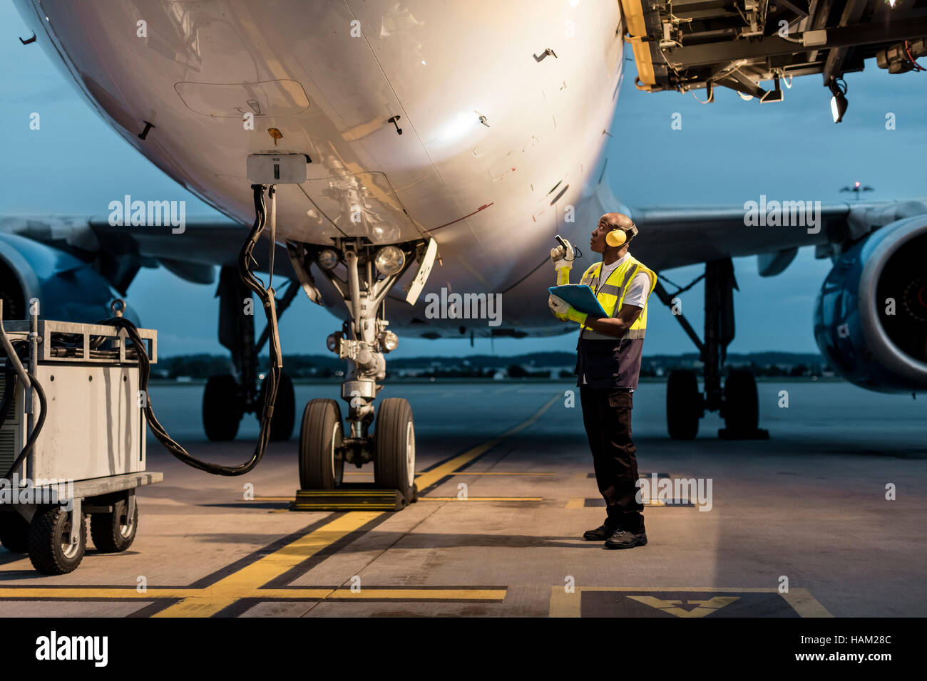 Airport ground crew worker checking airplane on tarmac Stock Photo - Alamy