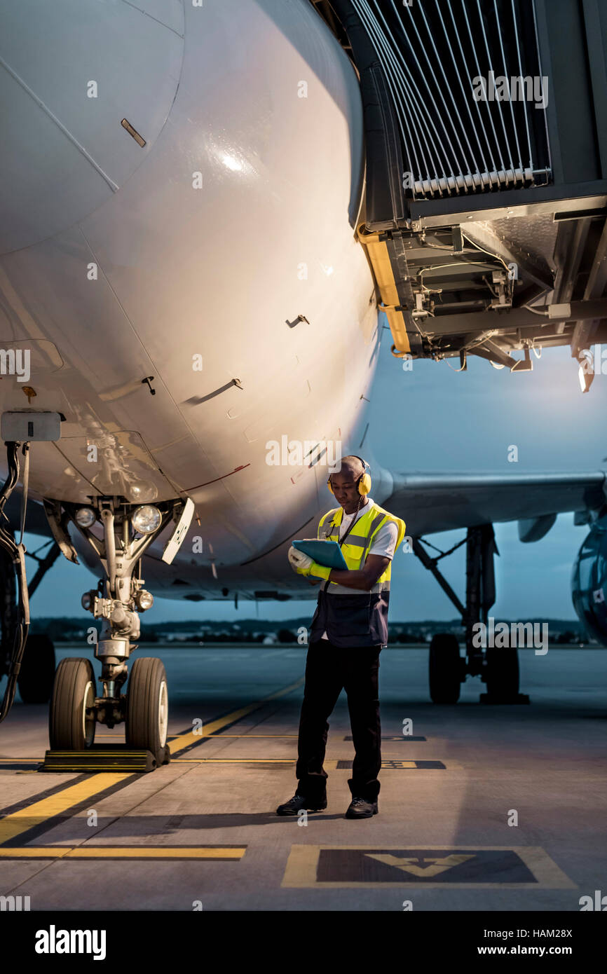 Airport ground crew worker with clipboard under airplane on tarmac ...