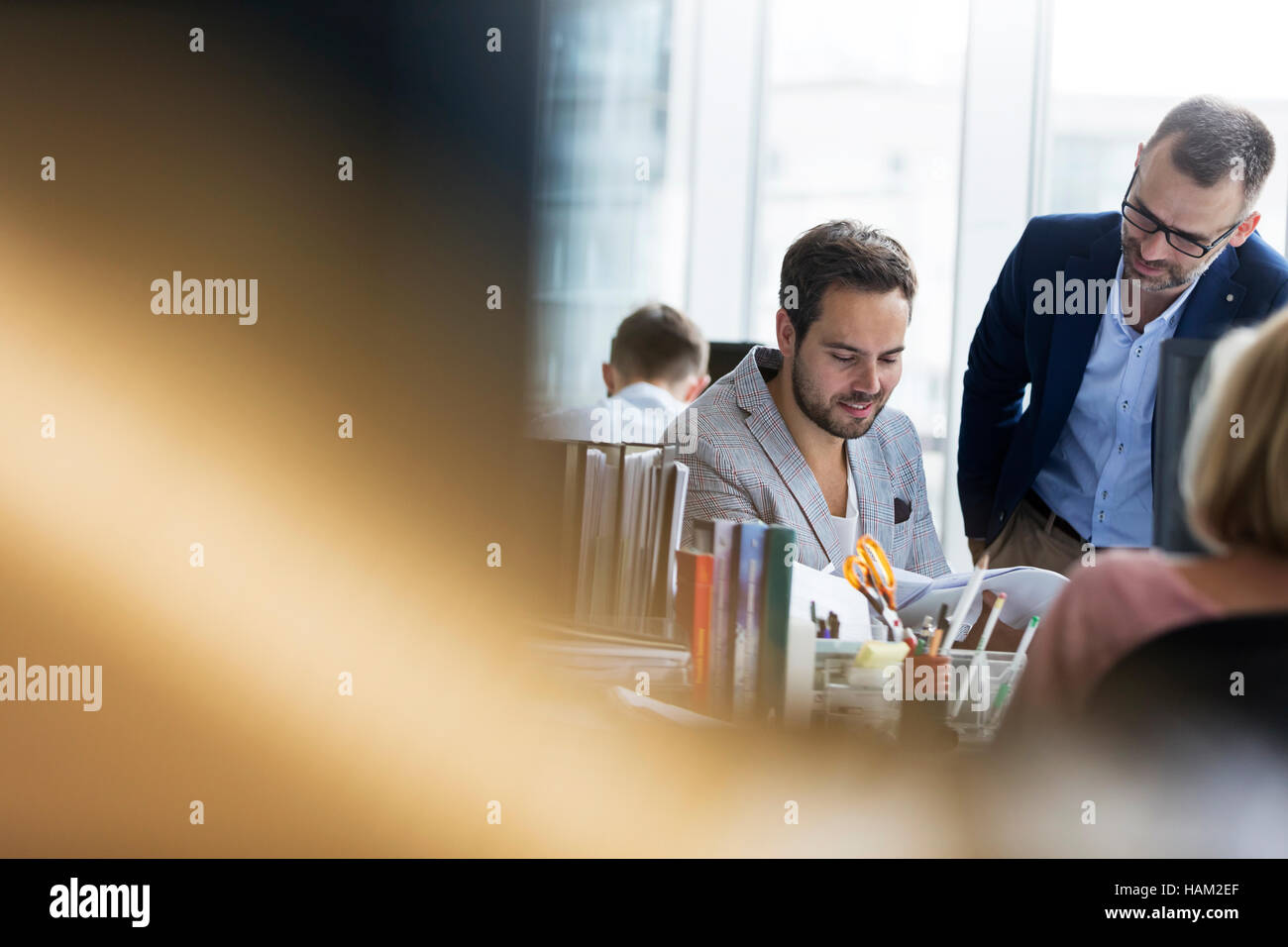 Business people reviewing paperwork at office desk Stock Photo - Alamy