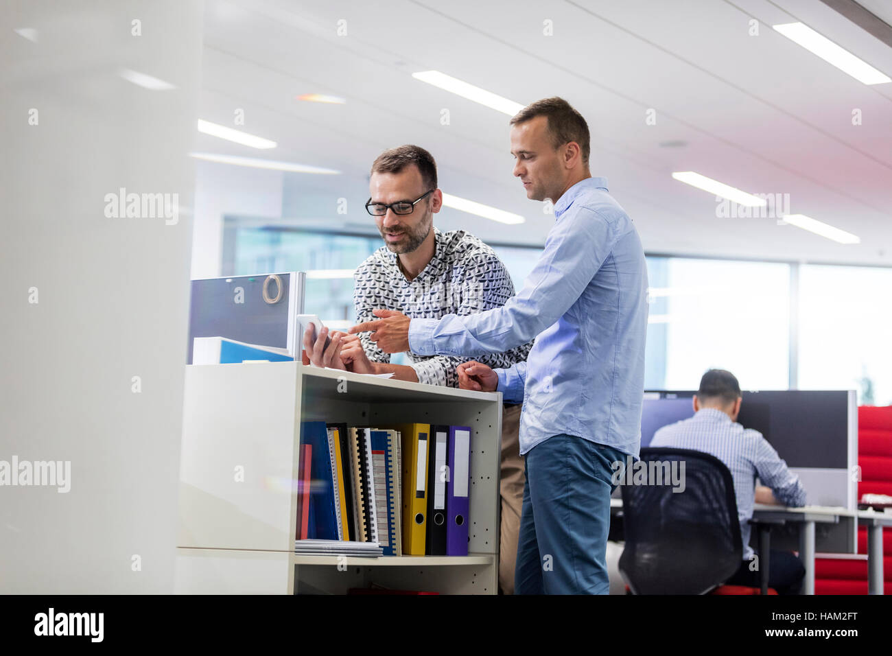 Businessmen using cell phone in office Stock Photo - Alamy