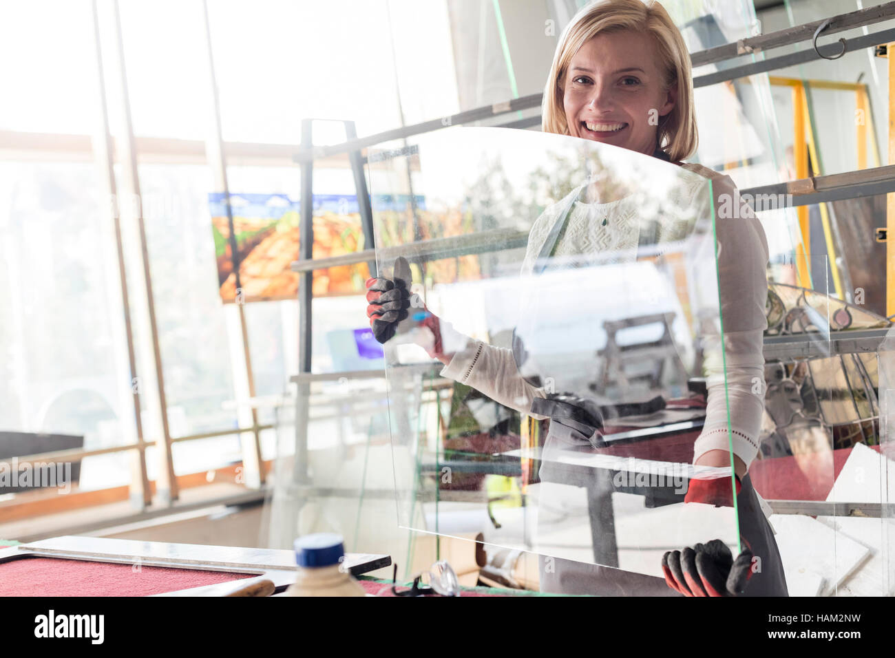 Portrait smiling stained glass artist lifting glass in studio Stock ...