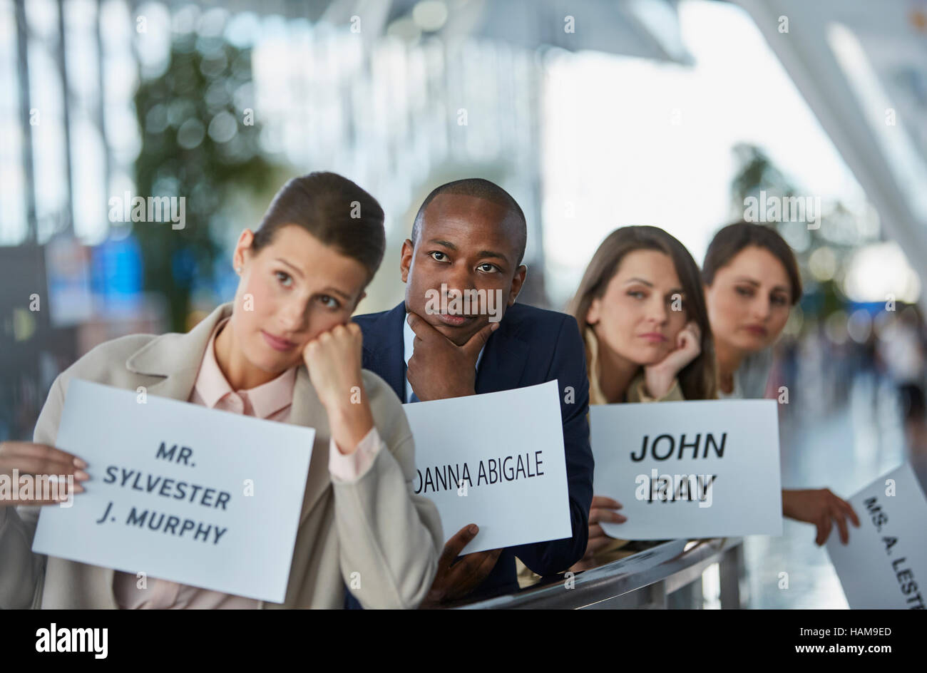 Bored chauffeurs waiting in a row with welcome signs at airport Stock ...