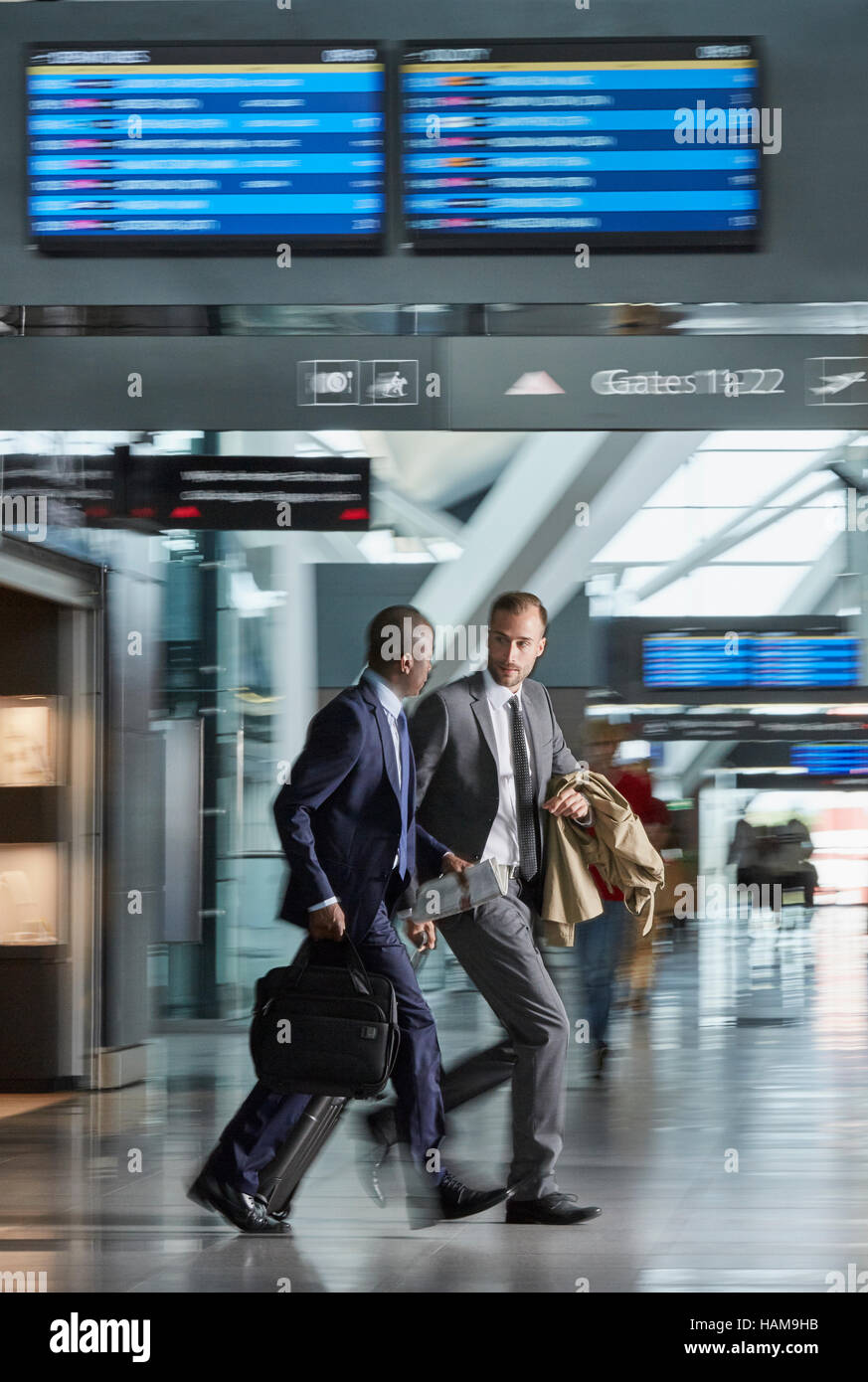 Businessmen running rushing in airport concourse Stock Photo - Alamy