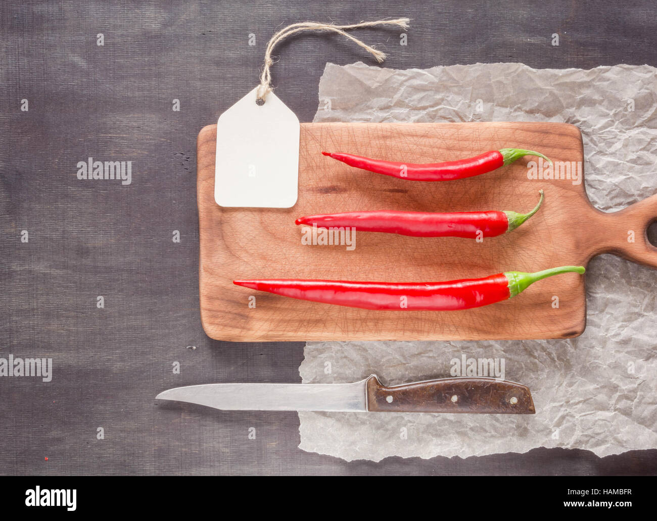 Three red fresh and sharp pepper on a cutting board. Dark background ...