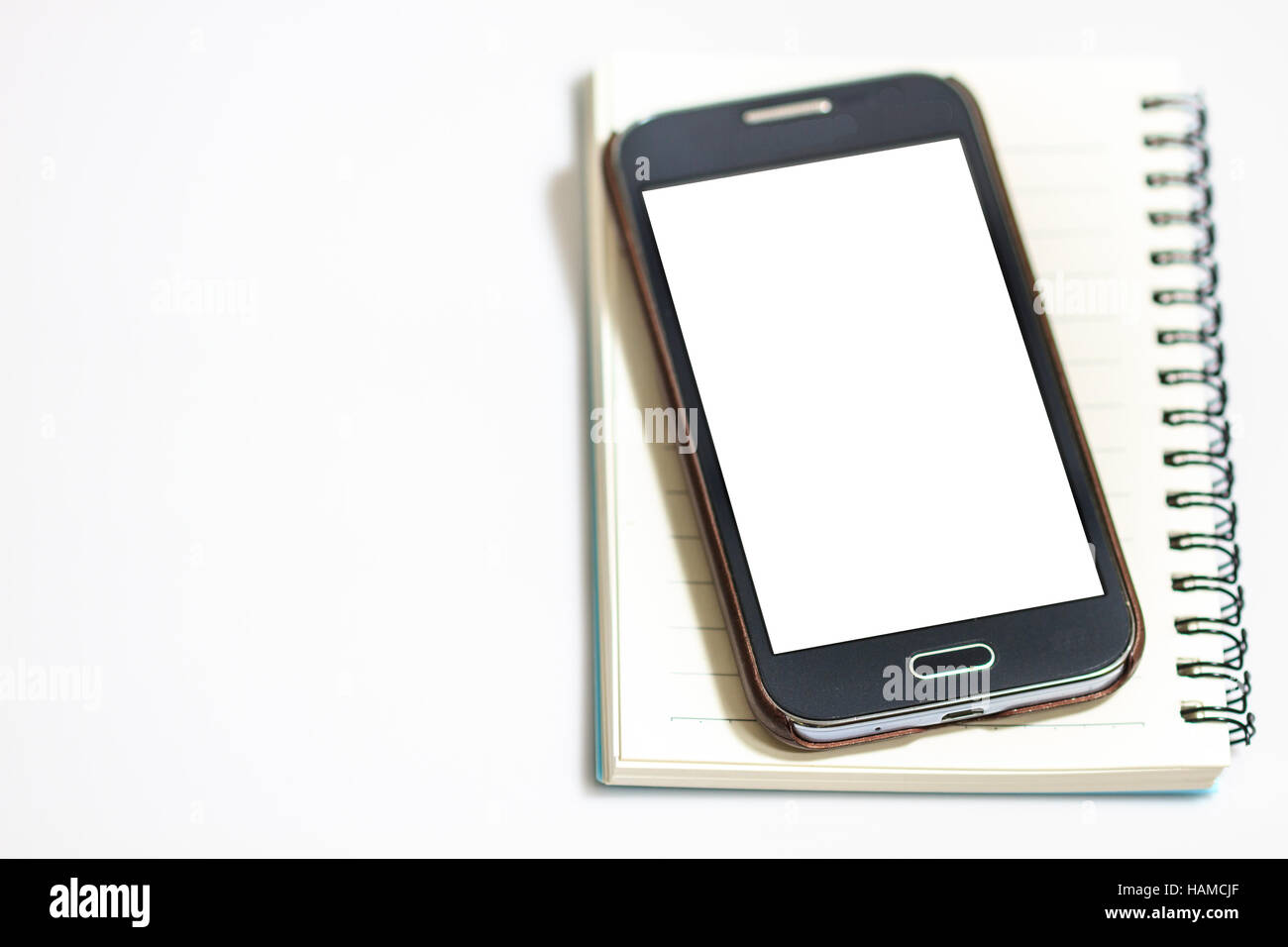 Opened notepad with smart phone on white background Stock Photo - Alamy