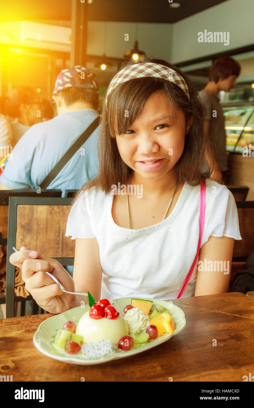 Asia girl eat cheesecake with cherry, kiwi, orange and grape at ...