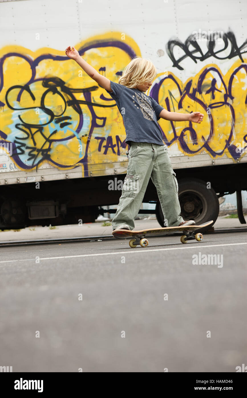 long blonde haired boy falling on skateboard past truck with graffiti ...
