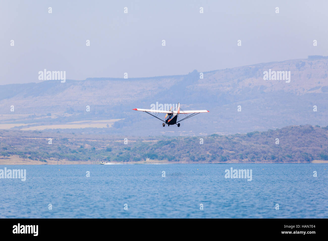 Plane Microlight pilot low flying aircraft photo over lake waters ...
