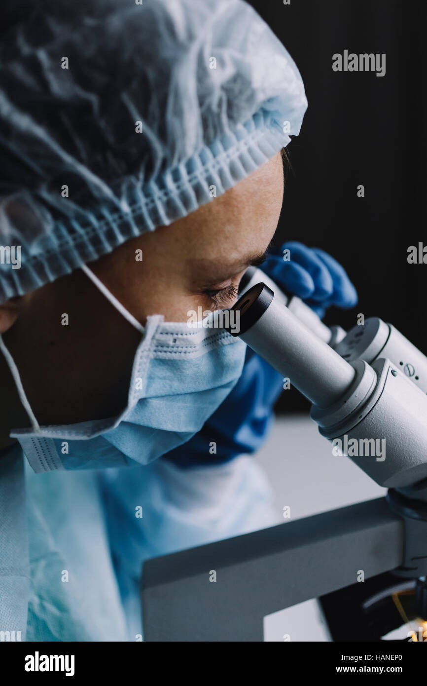 Female scientist looking at microscope Stock Photo - Alamy