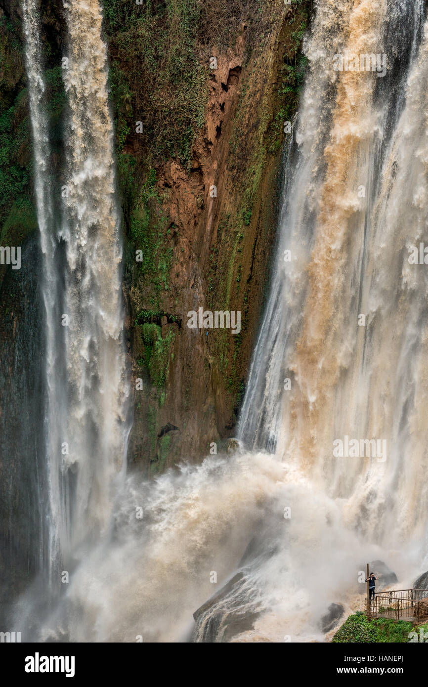 A young woman observes a large waterfall. Landscape with a human figure ...