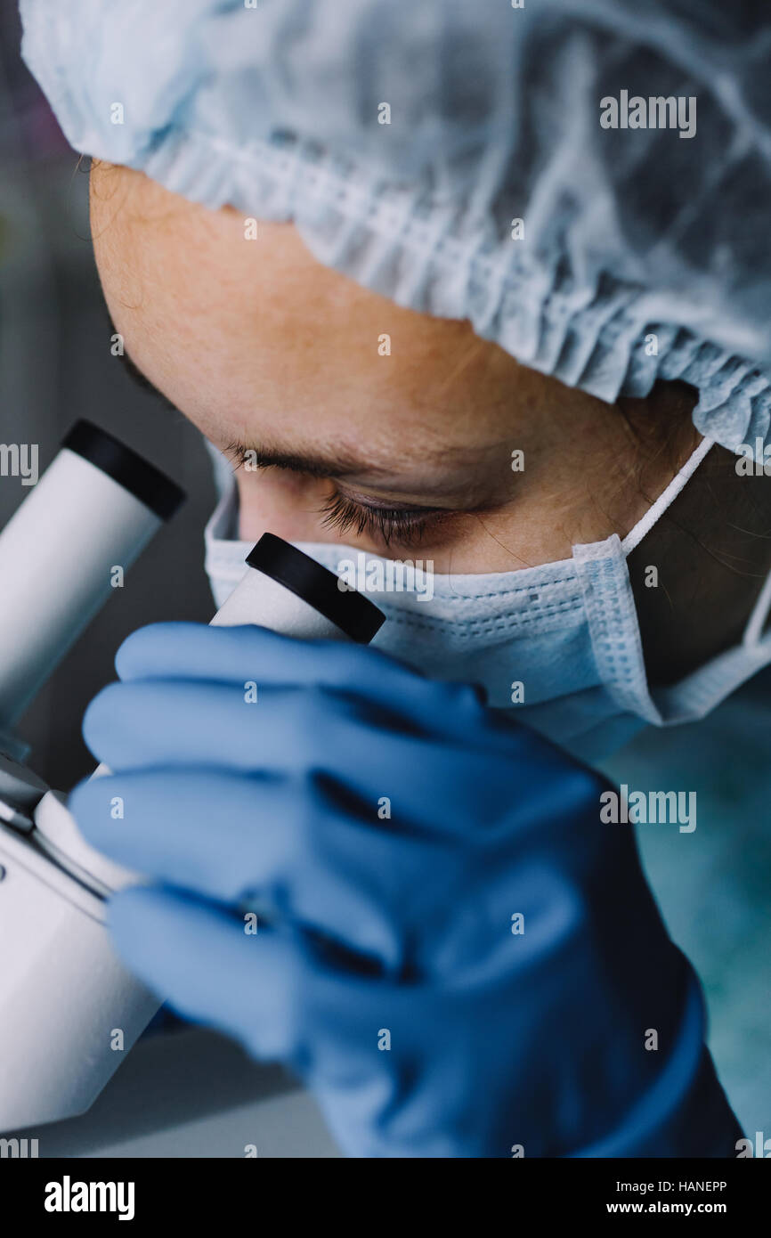 Young scientist in uniform looking at microscope Stock Photo - Alamy