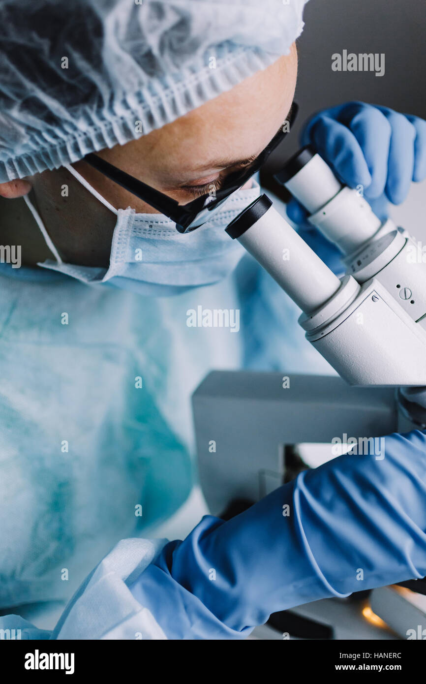 Young scientist in uniform looking at microscope Stock Photo - Alamy
