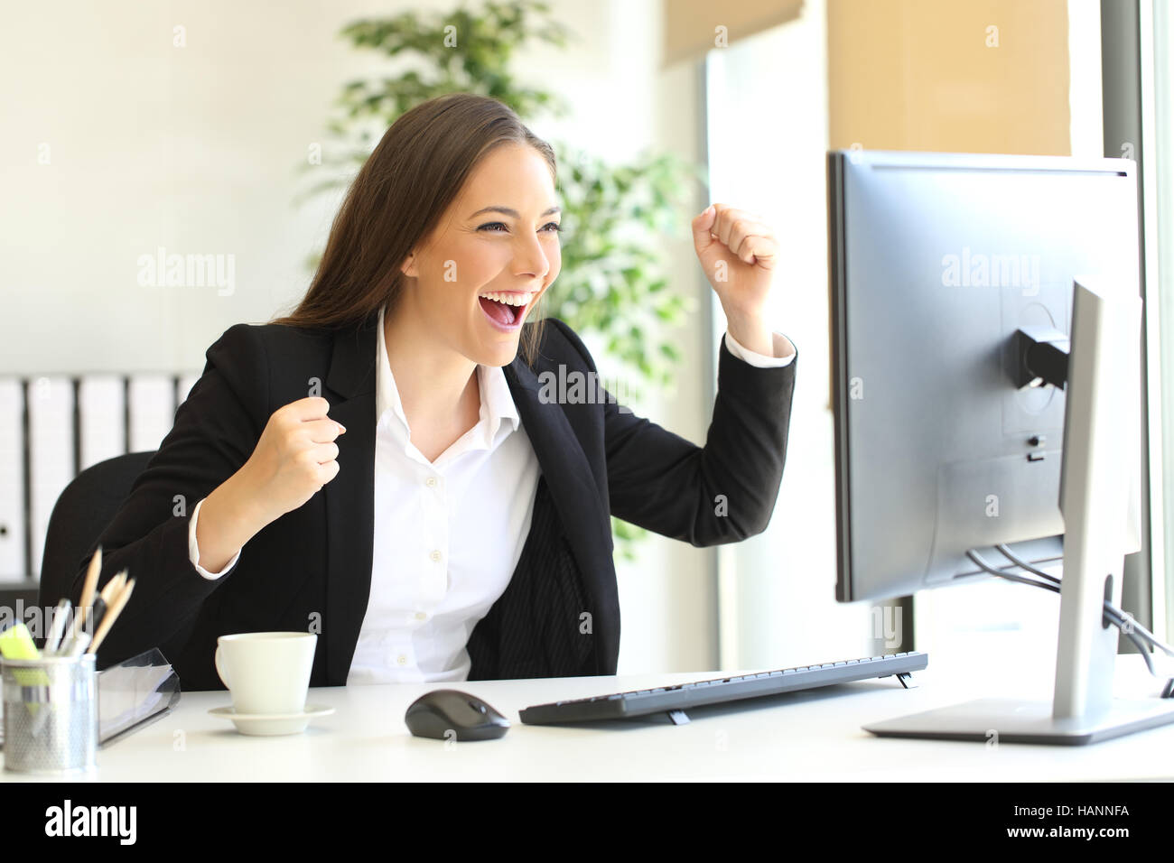 Excited executive wearing suit raising arms watching a desktop computer ...