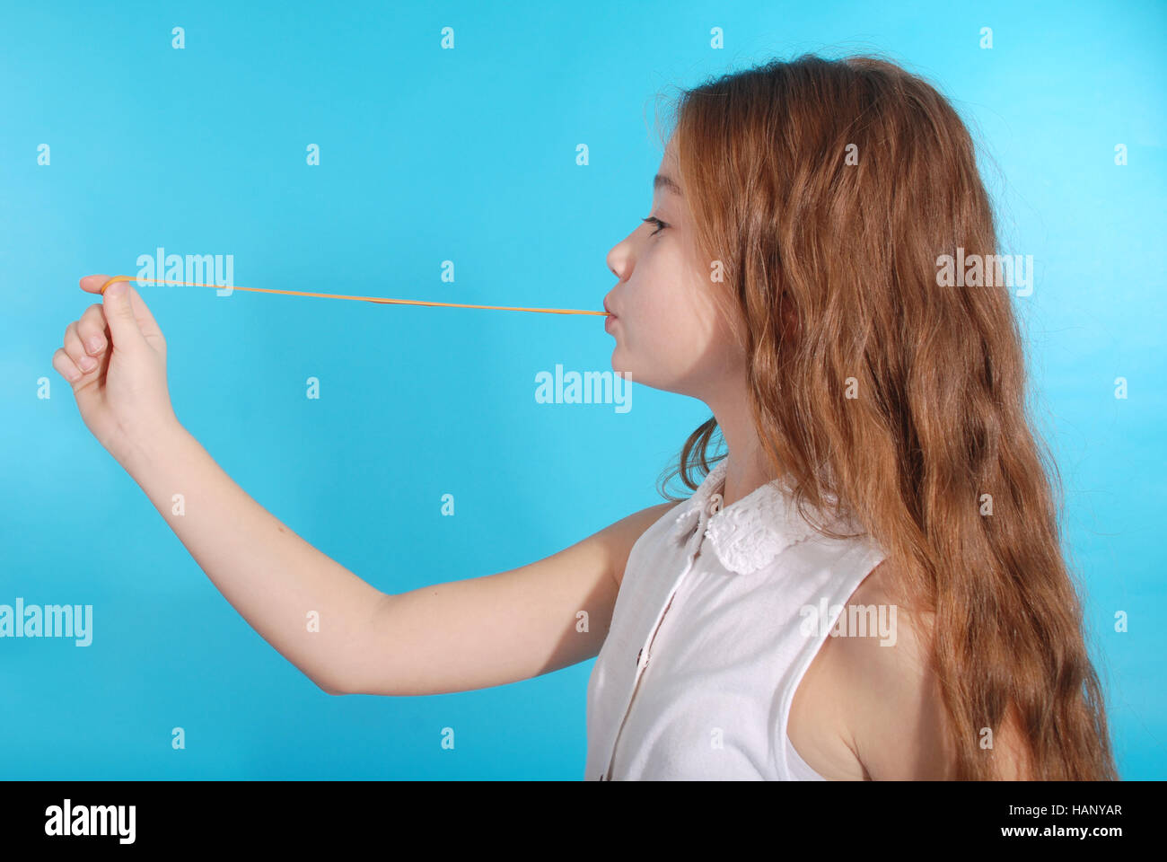Young girl playing with chewing gum isolated on blue Stock Photo - Alamy