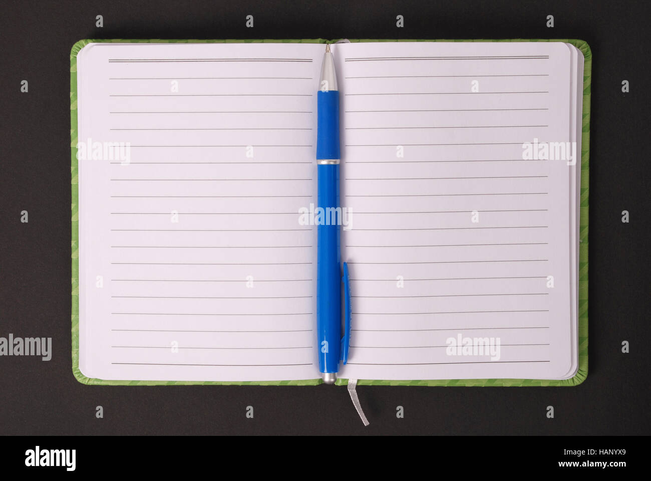 Green open notebook with blue pen isolated on black background red soft ...