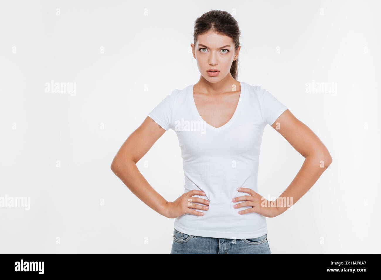 Serious model in t-shirt with arms at hips. isolated white background ...