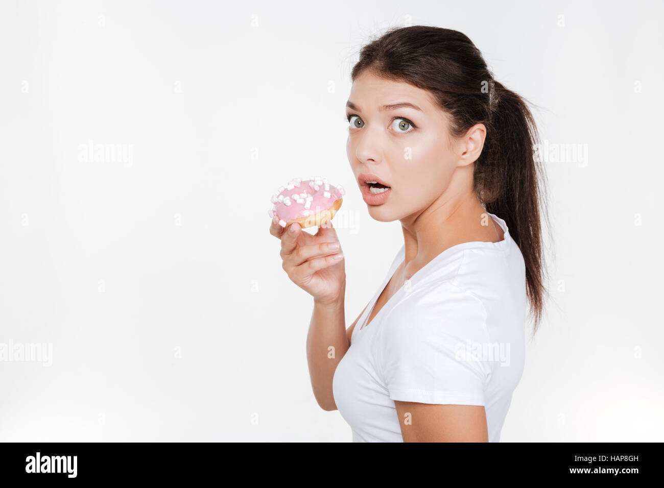 Image of confused diet young woman holding tasty donut isolated over ...