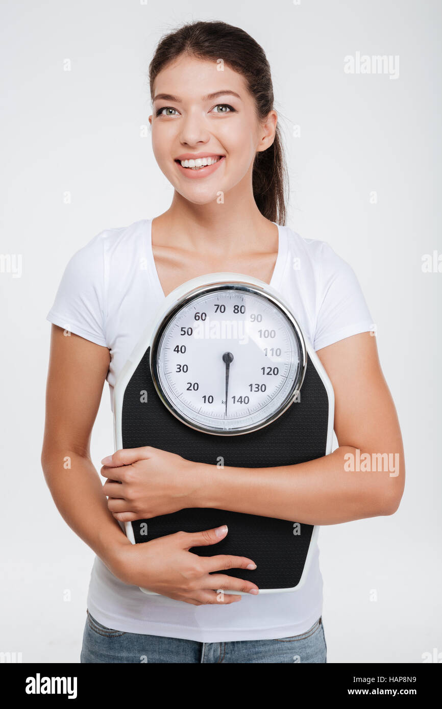 Smiling model in t-shirt with weight scale in studio. Isolated white ...