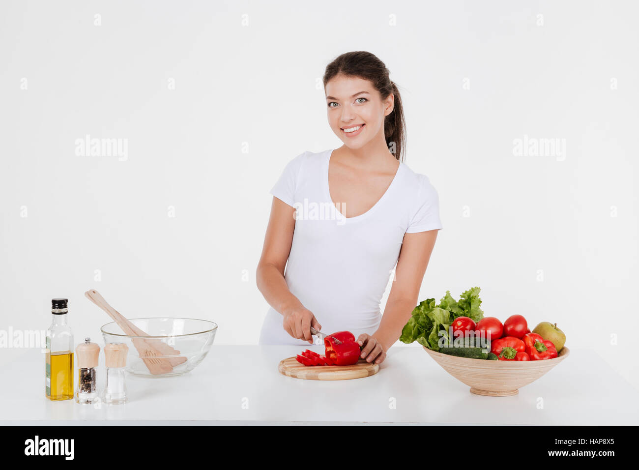 Happy young lady cooking with vegetables. Isolated on white background ...