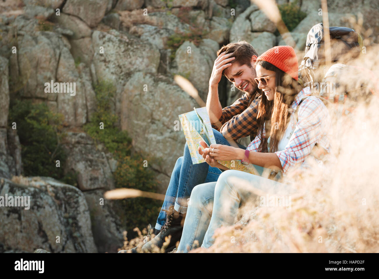 Adventure couple with map sitting on slope Stock Photo - Alamy