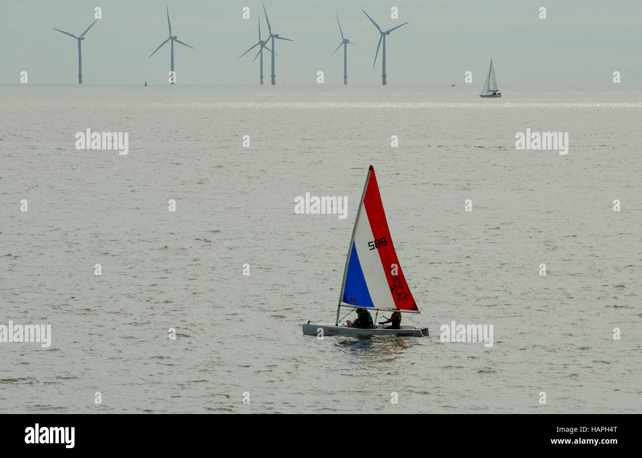 A small sailing dinghy containing young people on the sea, with wind ...
