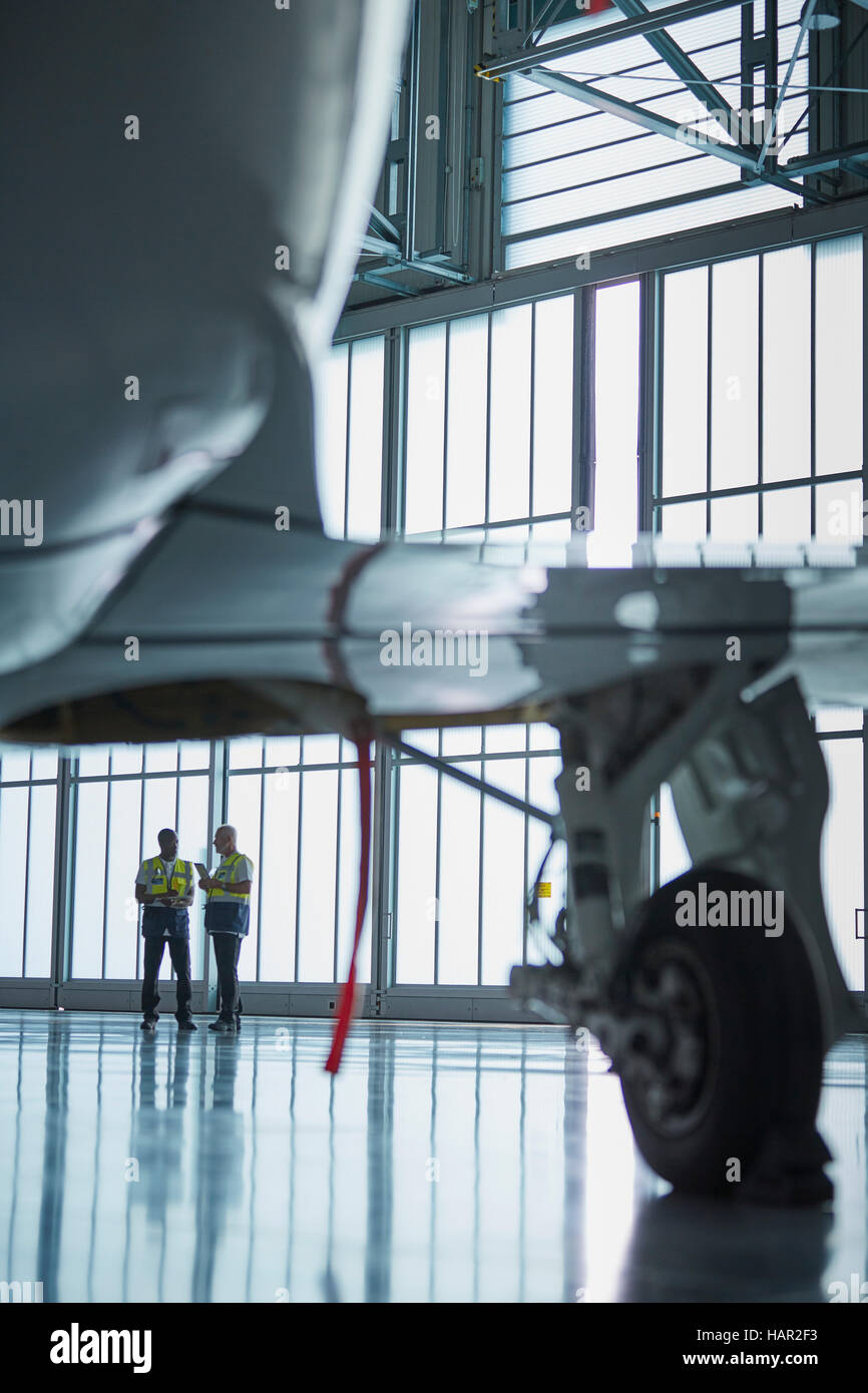 Air traffic control ground crew workers talking in airplane hangar ...