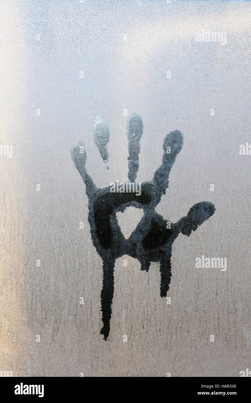 Impression of hand melted into hoar frost on greenhouse window. Backlit ...