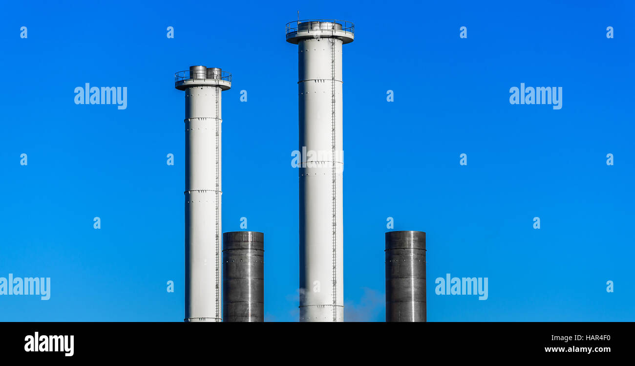 Modern industrial metallic chimneys isolated against a blue sky Stock ...