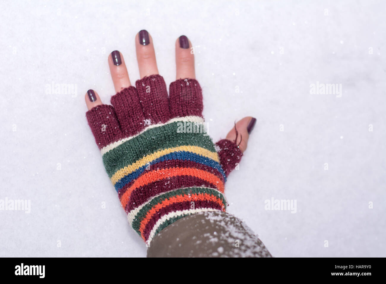 Hand in winter gloves touching snow covered covered ground in park ...