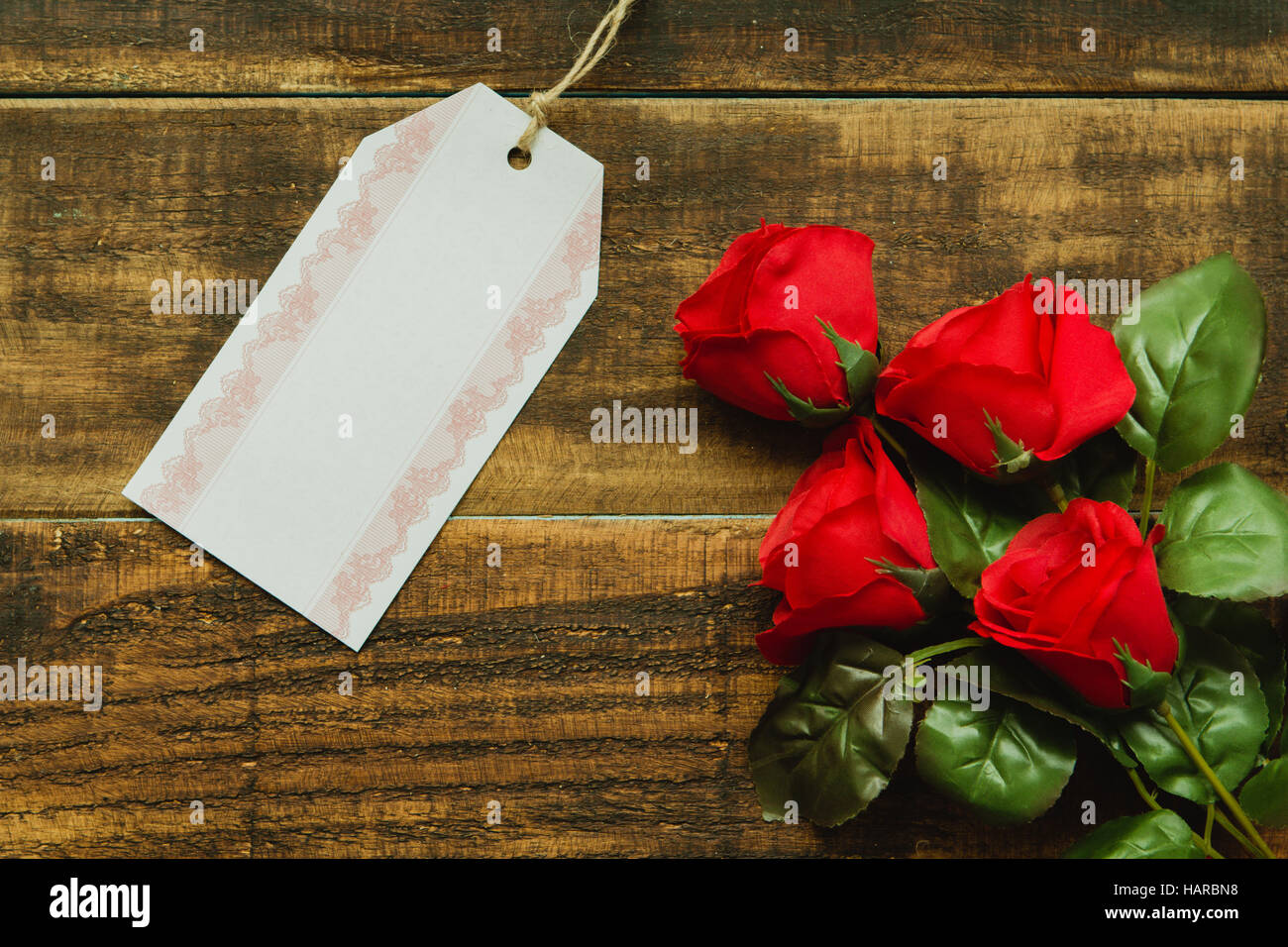 Tag template next to a red bouquet of roses on a rustic wood background ...