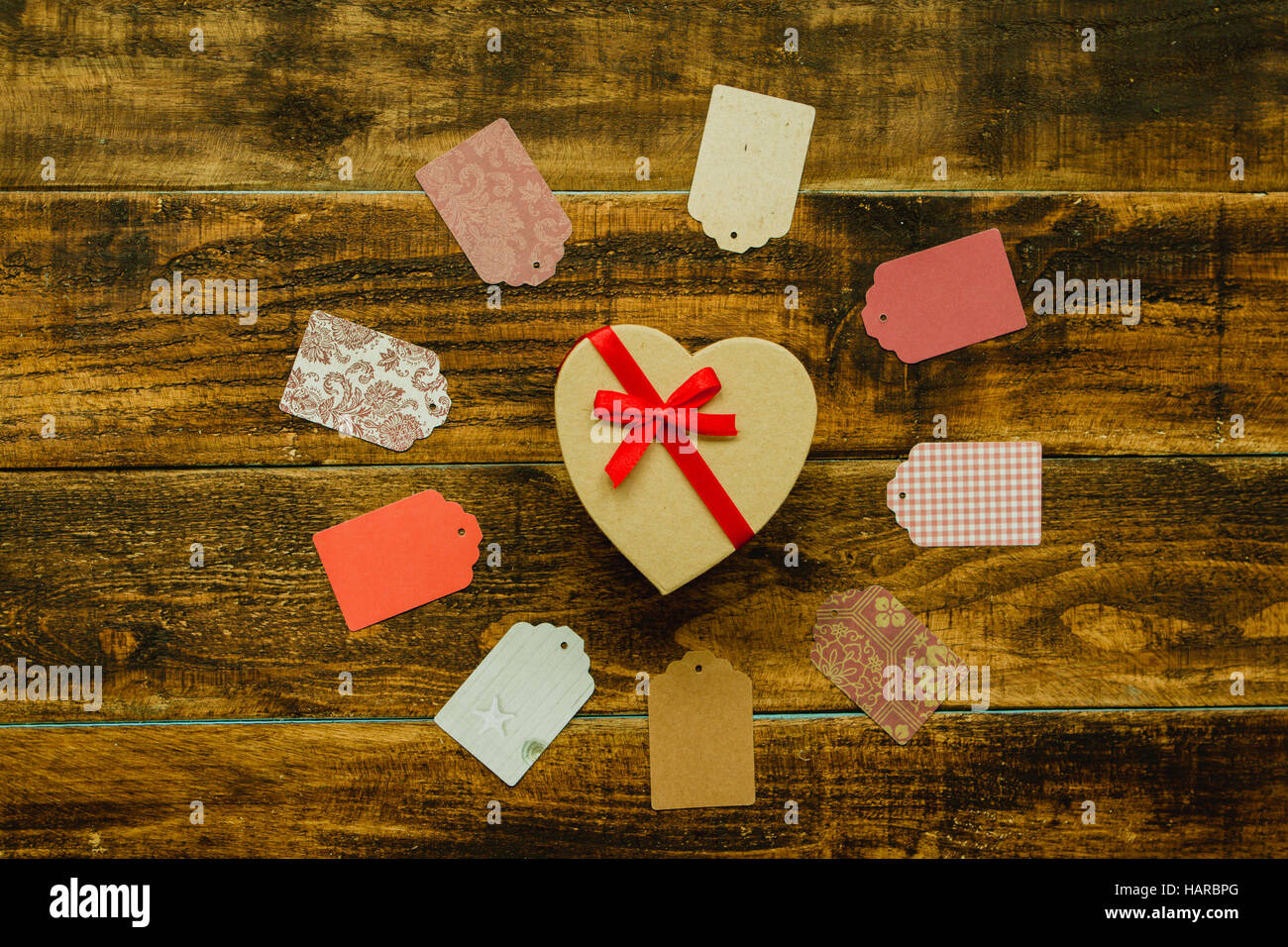 Beautiful gift with heart shape and red ribbon on a wooden background ...