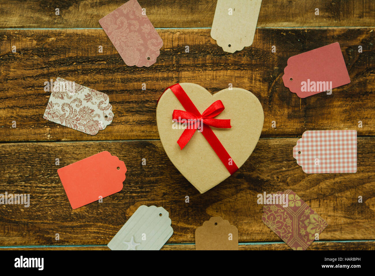 Beautiful gift with heart shape and red ribbon on a wooden background ...