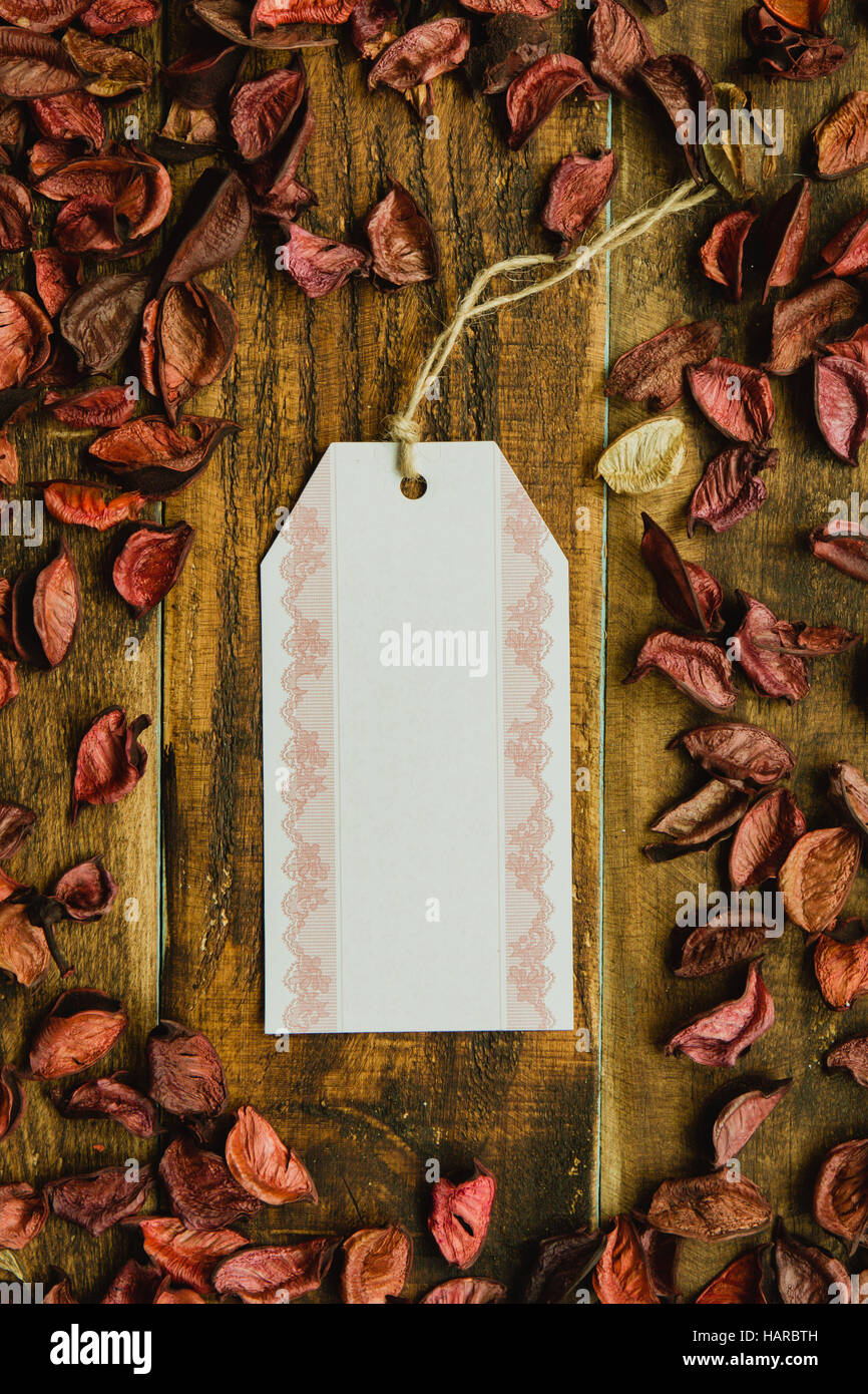 Empty shopping tag template around dry petals on a rustic wood ...