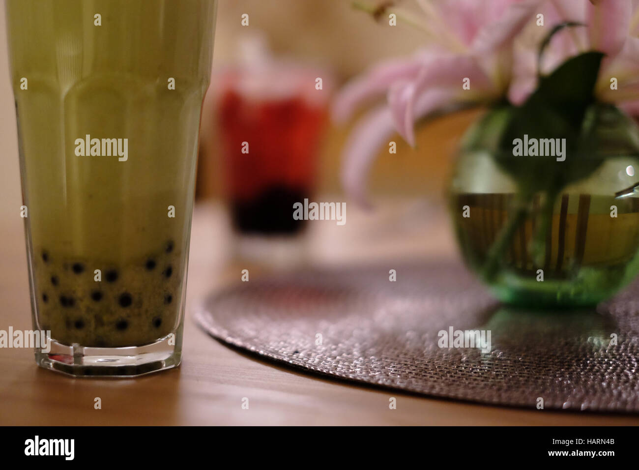 Two tall glasses of bubble tea, one green with a straw, in the ...