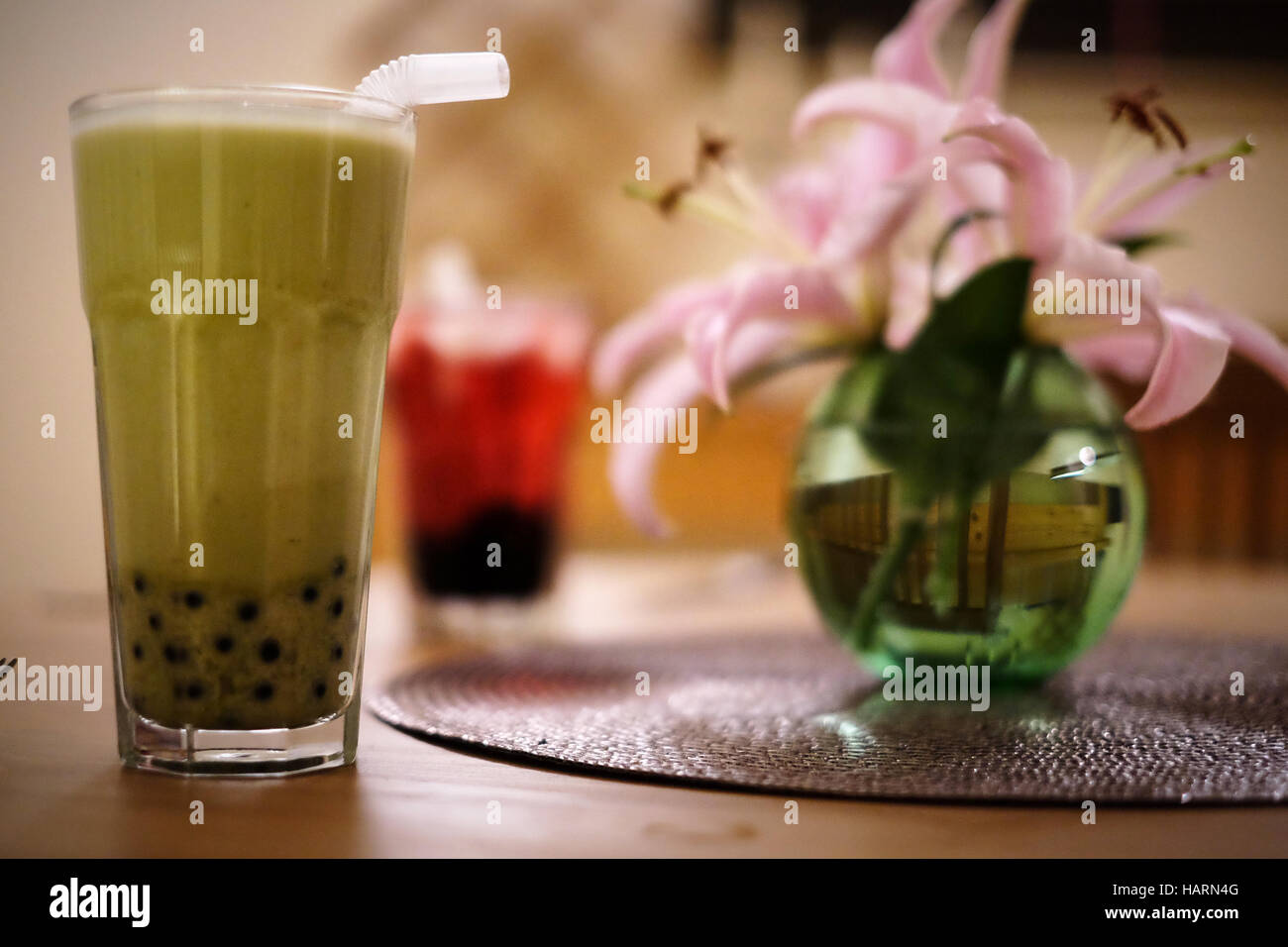 Two tall glasses of bubble tea, one green with a straw, in the ...