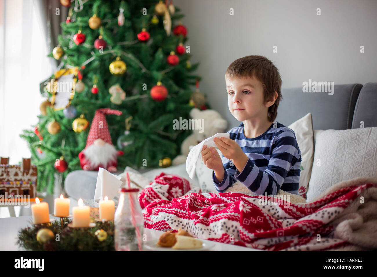Little child, boy, blowing his nose and sneezing, lying sick in bed on ...
