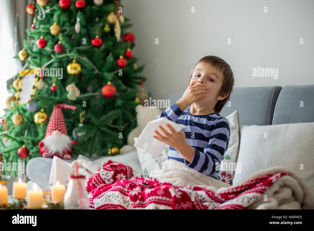 Little child, boy, blowing his nose and sneezing, lying sick in bed on ...