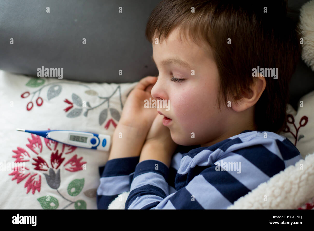 Sick little child, boy, with high fever sleeping on the couch at home ...